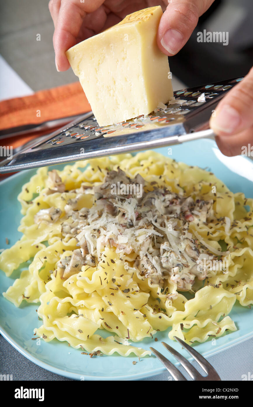 grating a piece of cheese on pasta plate Stock Photo - Alamy