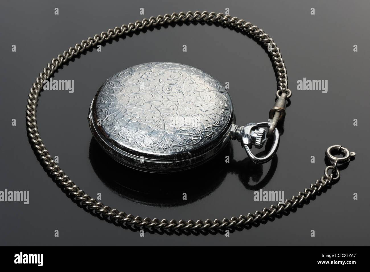 pocket watch with closed cover and their reflection on a black ...