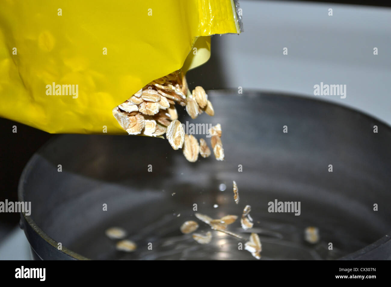 pouring oats into saucepan of water Stock Photo - Alamy