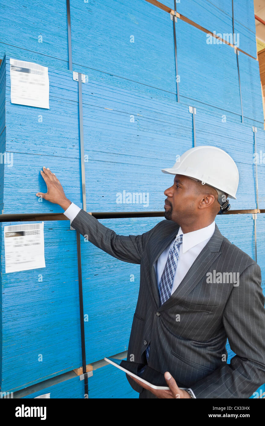 African American male contractor inspecting wooden planks while holding ...