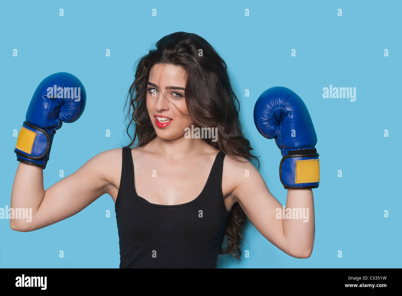 Portrait of a beautiful young female boxer raising arms in victory ...