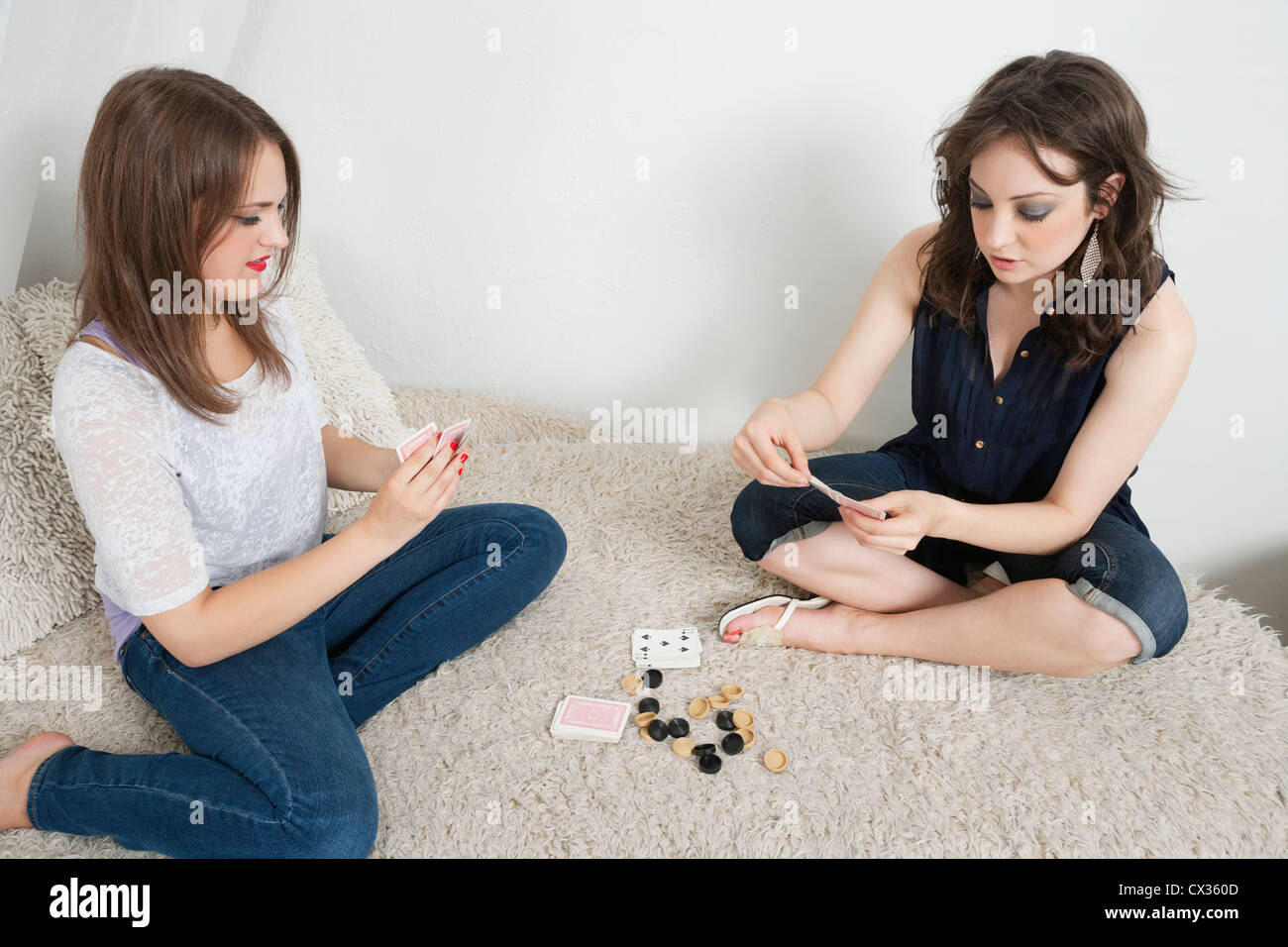 Young women playing cards while sitting on fur sofa Stock Photo - Alamy