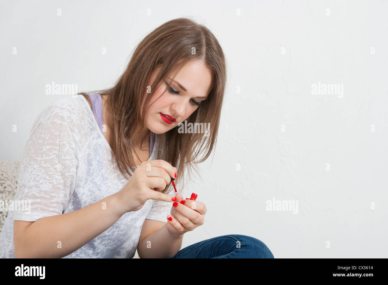 Beautiful young woman applying nail paint Stock Photo - Alamy