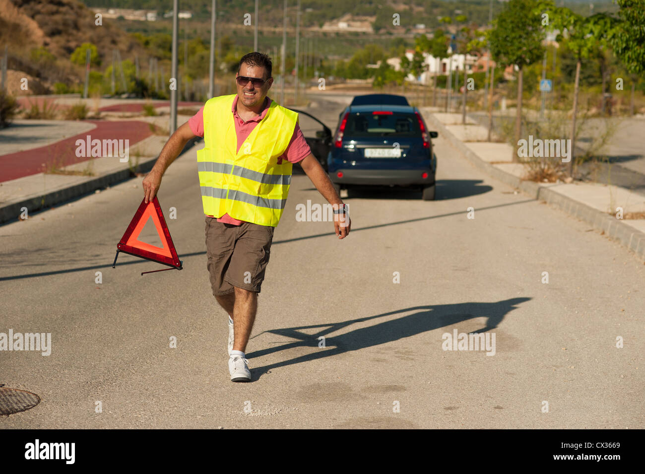 Guy carrying a triangle to warn of his breakdown Stock Photo - Alamy