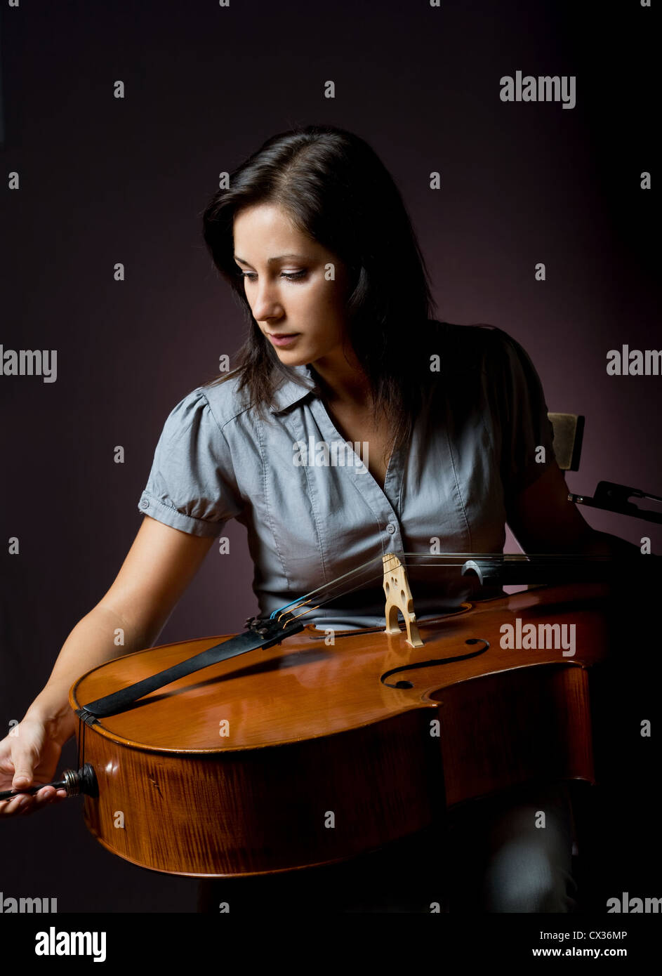 Preparing to perform, beautiful young cellist woman checking her ...