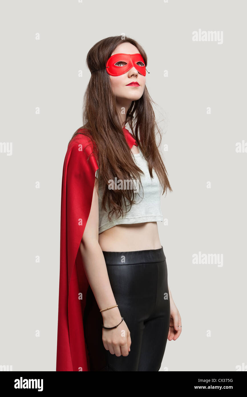 Young woman in superhero costume looking up against gray background ...