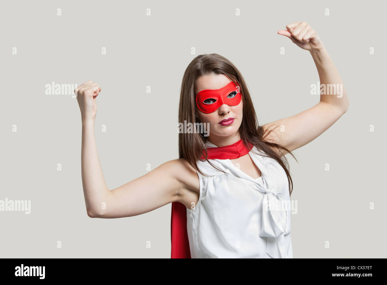 Portrait of a young woman in super hero costume flexing muscles over ...