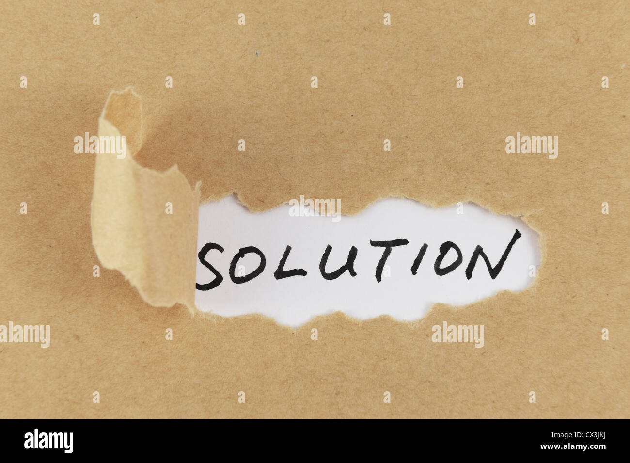 Torn paper with solution word behind it Stock Photo - Alamy