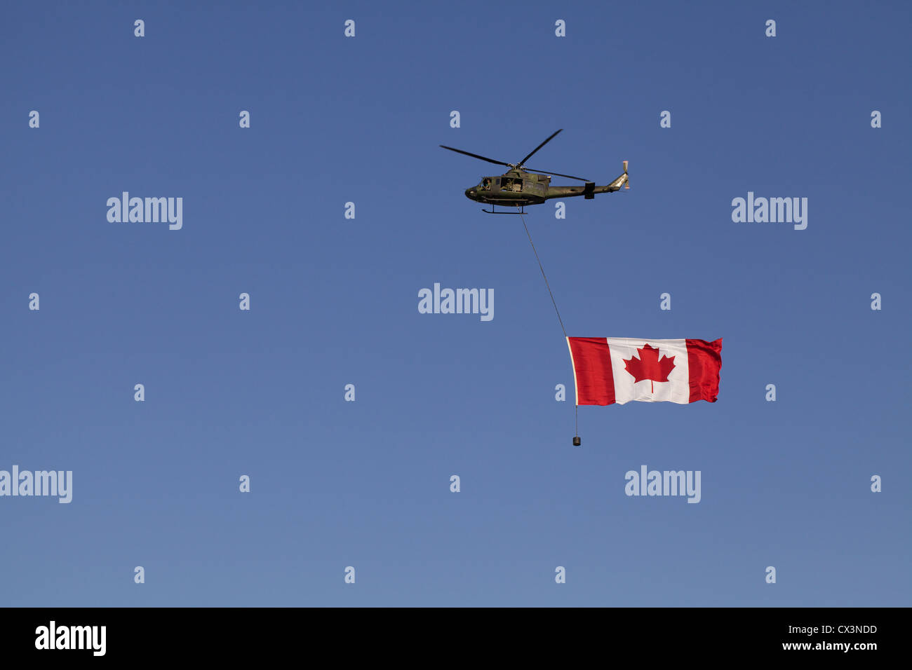 A helicopter carries the flag of Canada at the Calgary stampede event ...