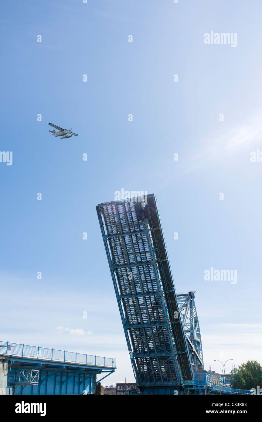 A float plane flies over a raised drawbridge Stock Photo - Alamy