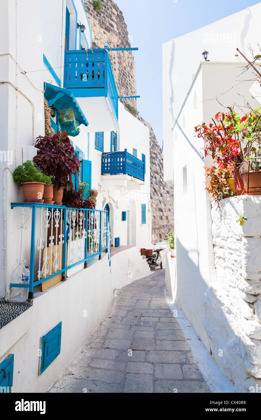 Narrow street in greek city with blue windows Stock Photo - Alamy