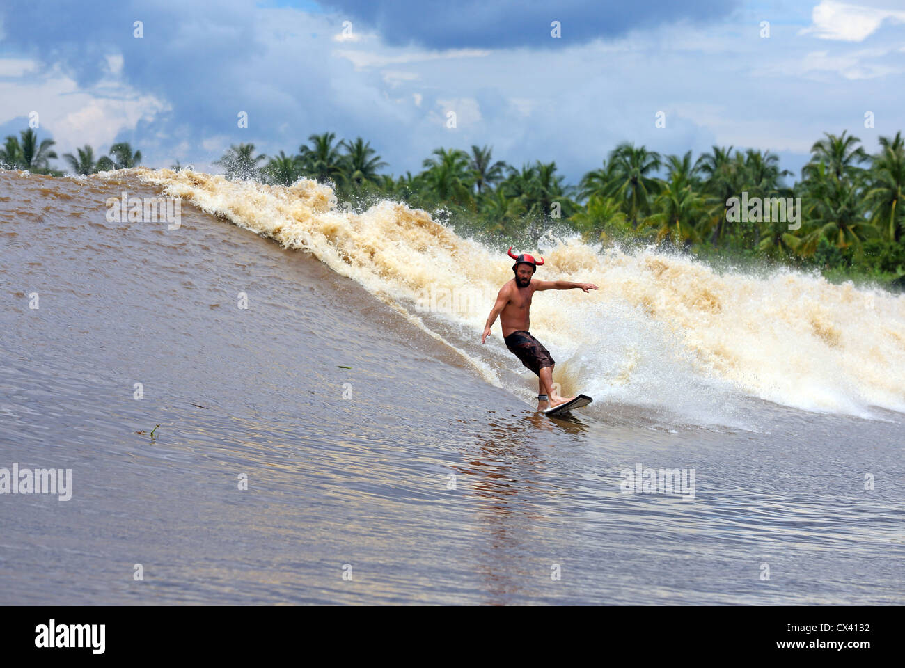 Surfing a tidal river bore wave on the Kampar River also known as the ...