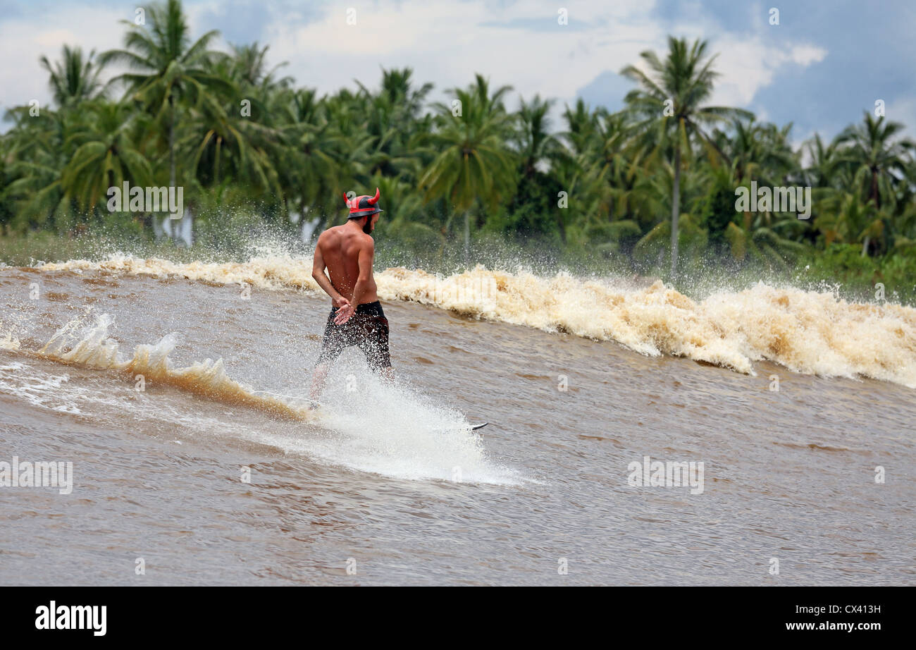 Surfing a tidal river bore wave on the Kampar River also known as the ...