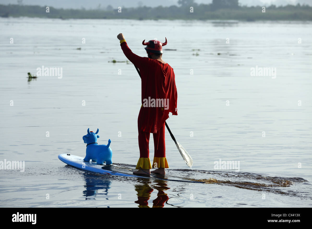 Man in red costume paddles a stand up paddle board (SUP) with a blue ...