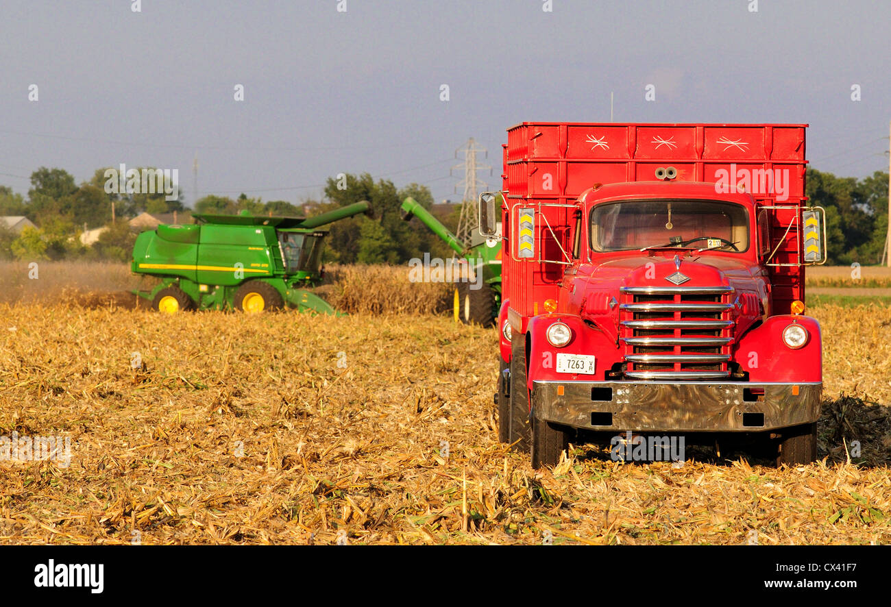 Harvesting corn with a John Deere combine and tractor hauling grain wagon and offloading the ...
