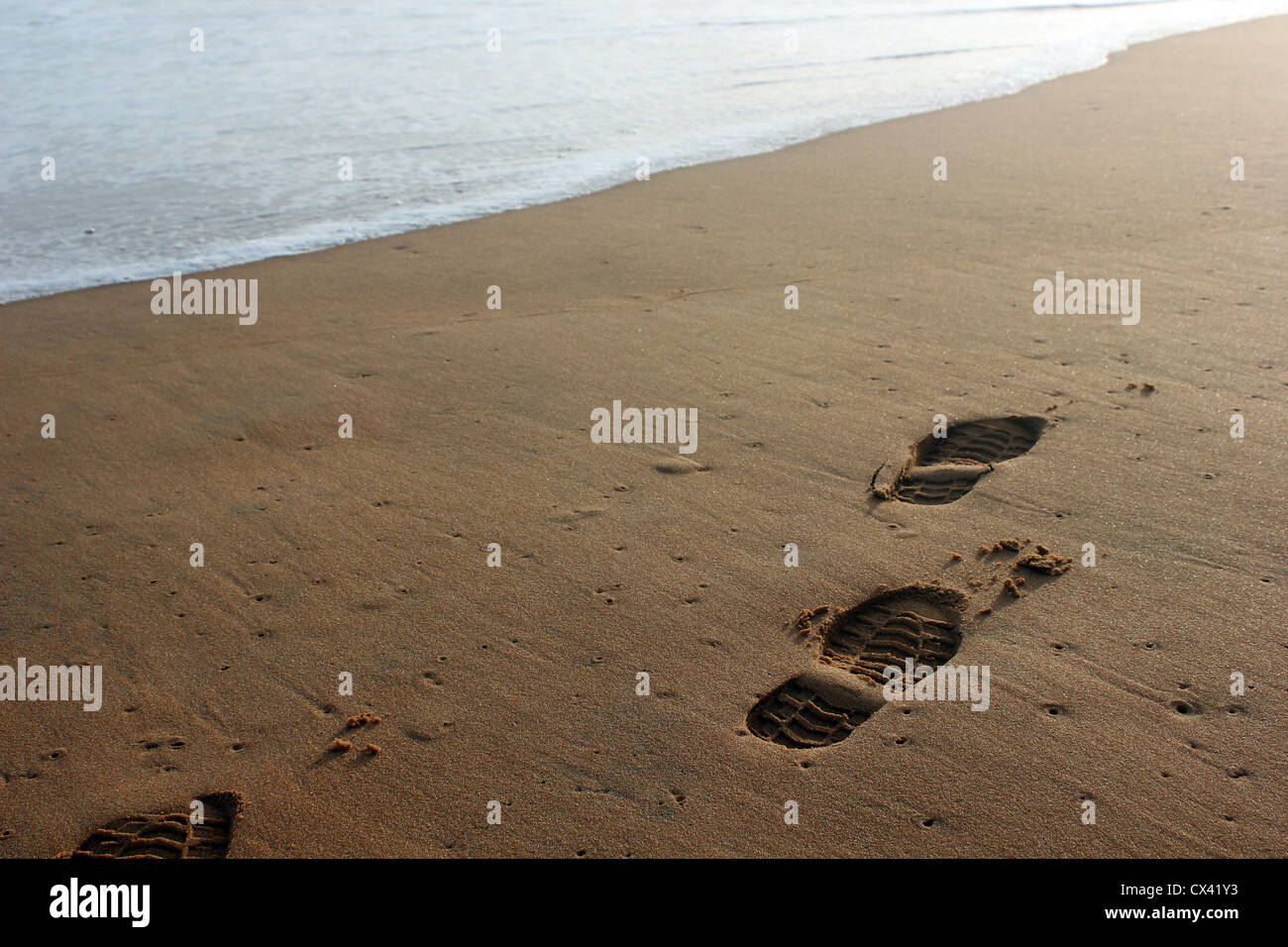 Footprint or shoe print on a beach close to the waves Stock Photo - Alamy