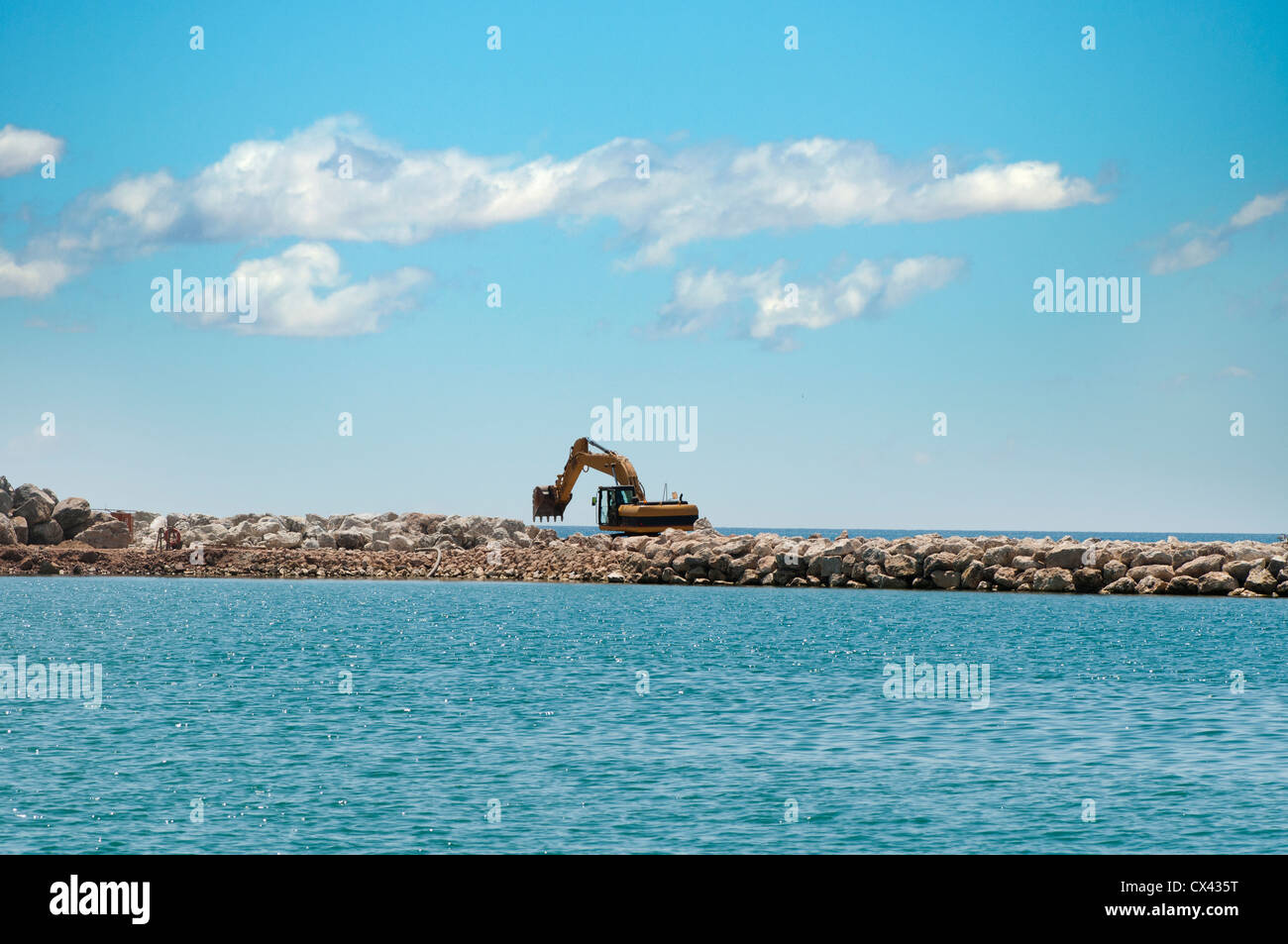 Building a dike. Excavator put stones in the sea Stock Photo - Alamy