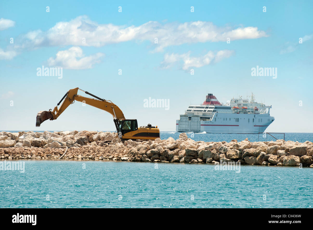 Building a dike. Excavator put stones in the sea. A ship on background ...