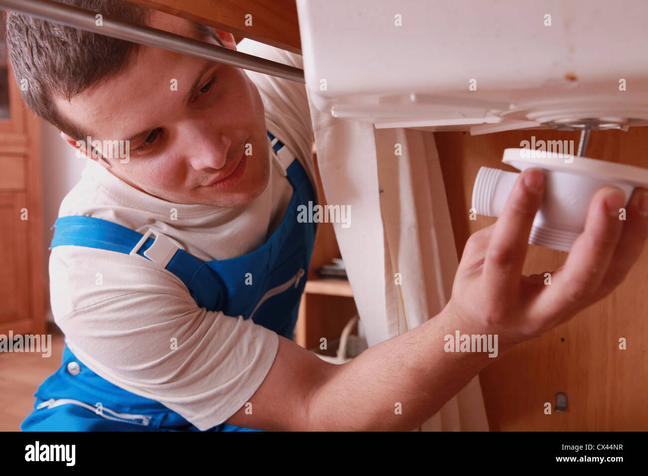 Plumber fixing sink Stock Photo - Alamy