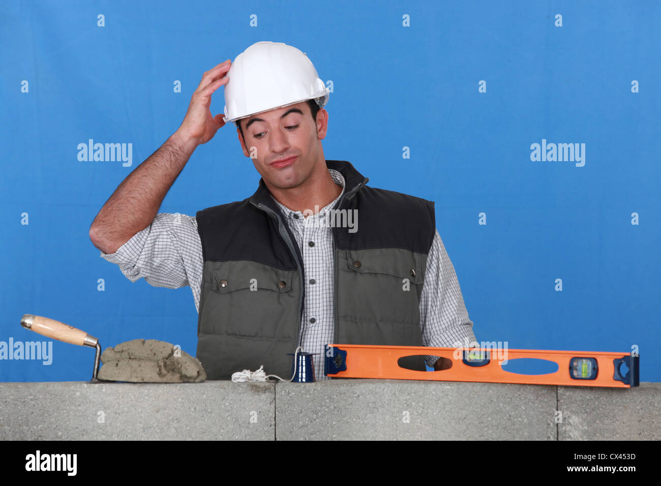 Confused mason stood by unfinished wall Stock Photo - Alamy