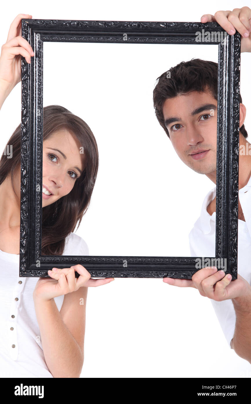 Man and woman holding up a picture frame Stock Photo - Alamy