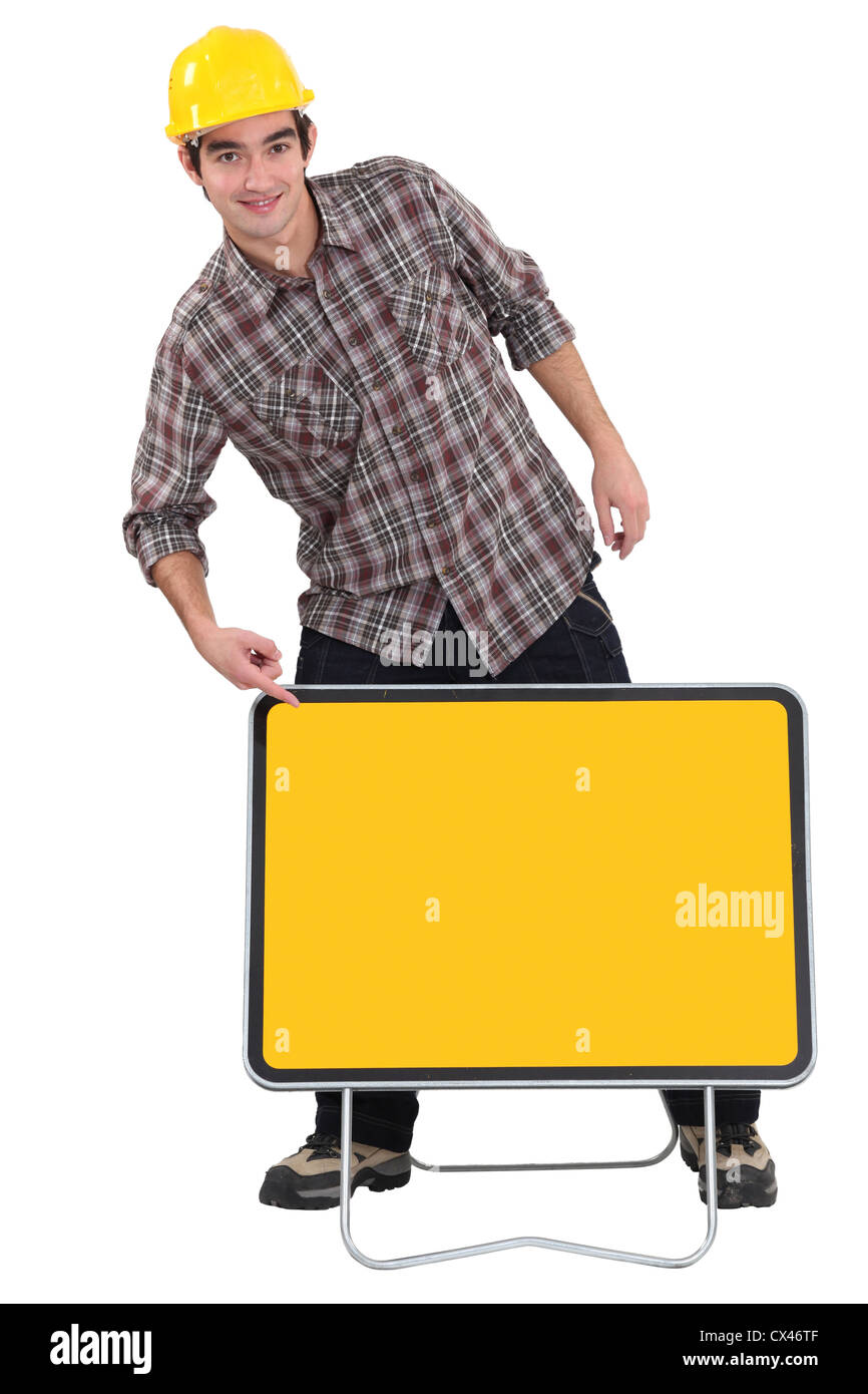 Construction worker pointing to a blank yellow sign Stock Photo - Alamy