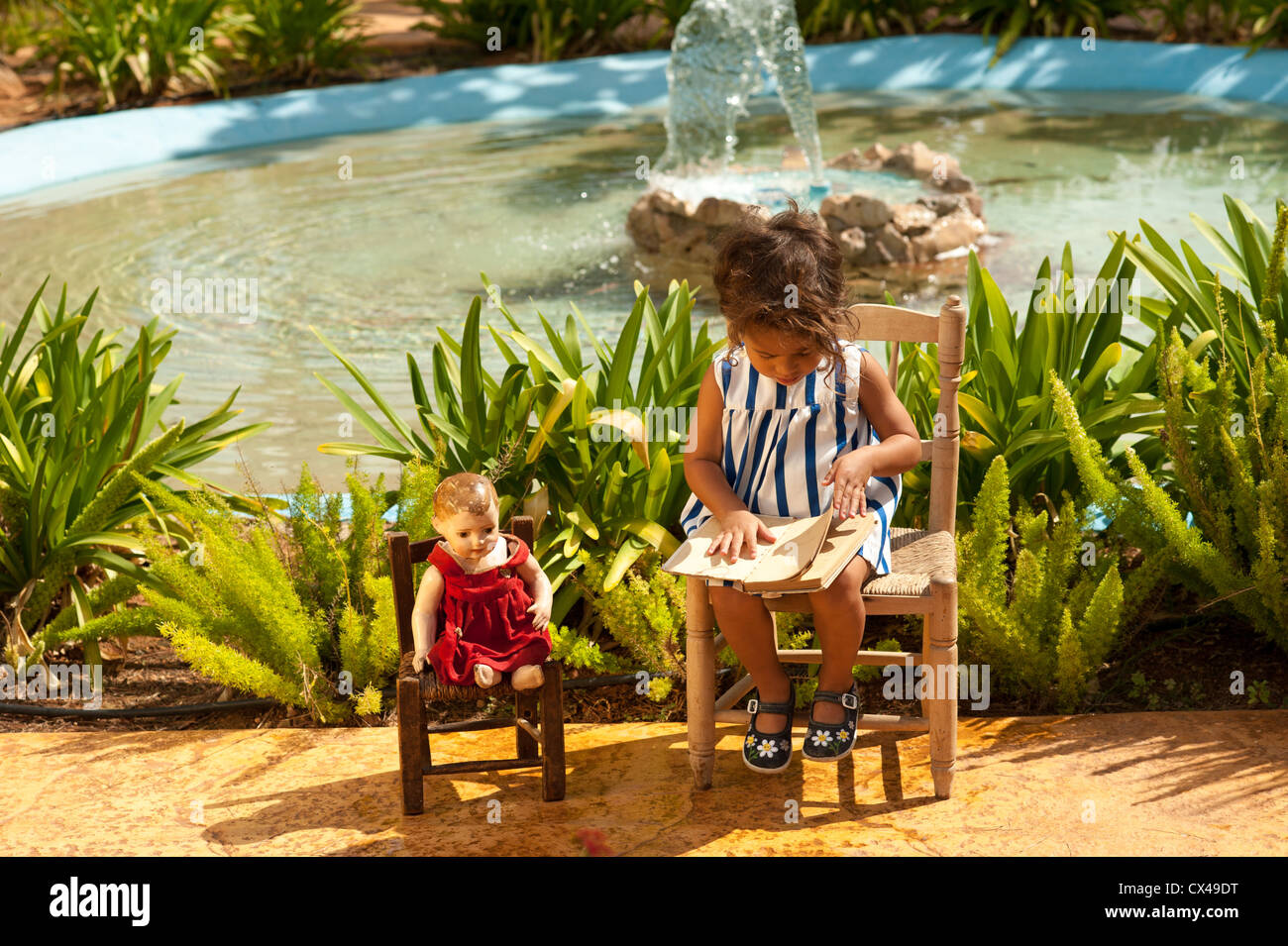 Cute little girl reading to her vintage doll from an old book Stock ...