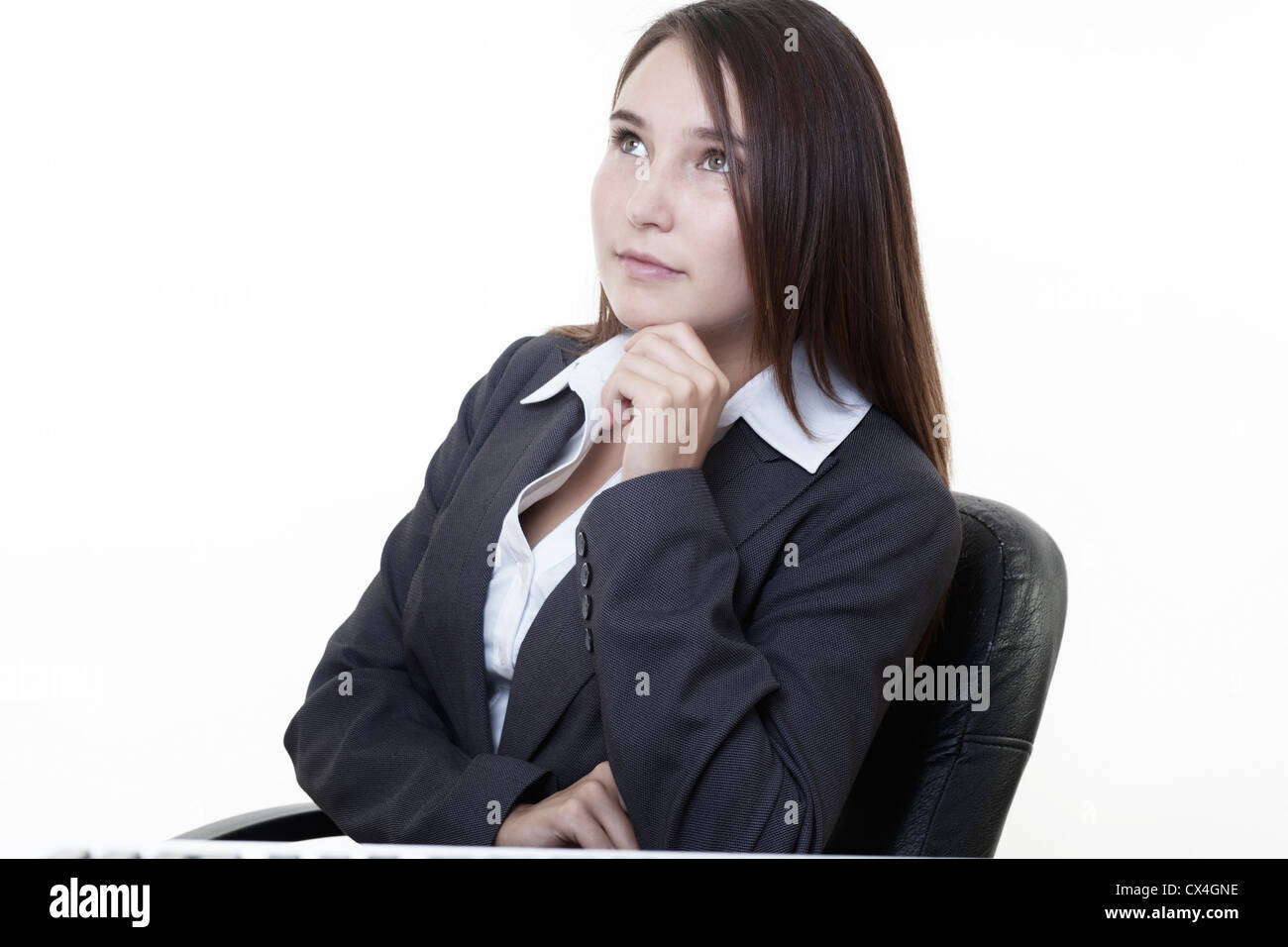 young looking woman sitting at her desk deep in thought Stock Photo - Alamy