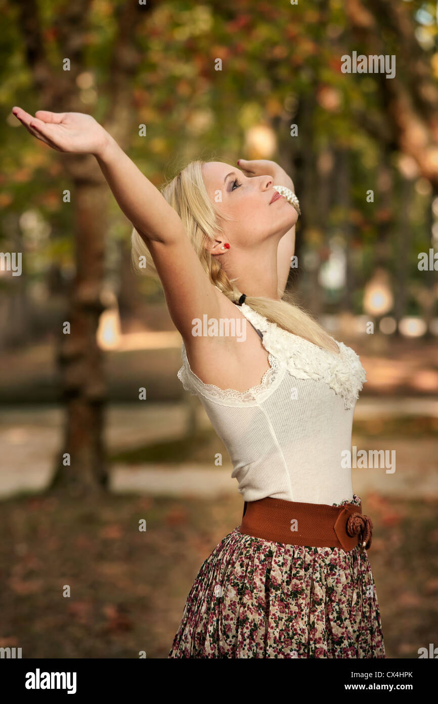 Portrait of a beautiful young woman relaxing with arms open and ...