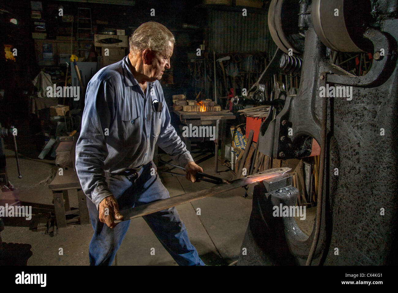 An elderly blacksmith in a Tustin, CA, barn built in 1912 carries a hot ...