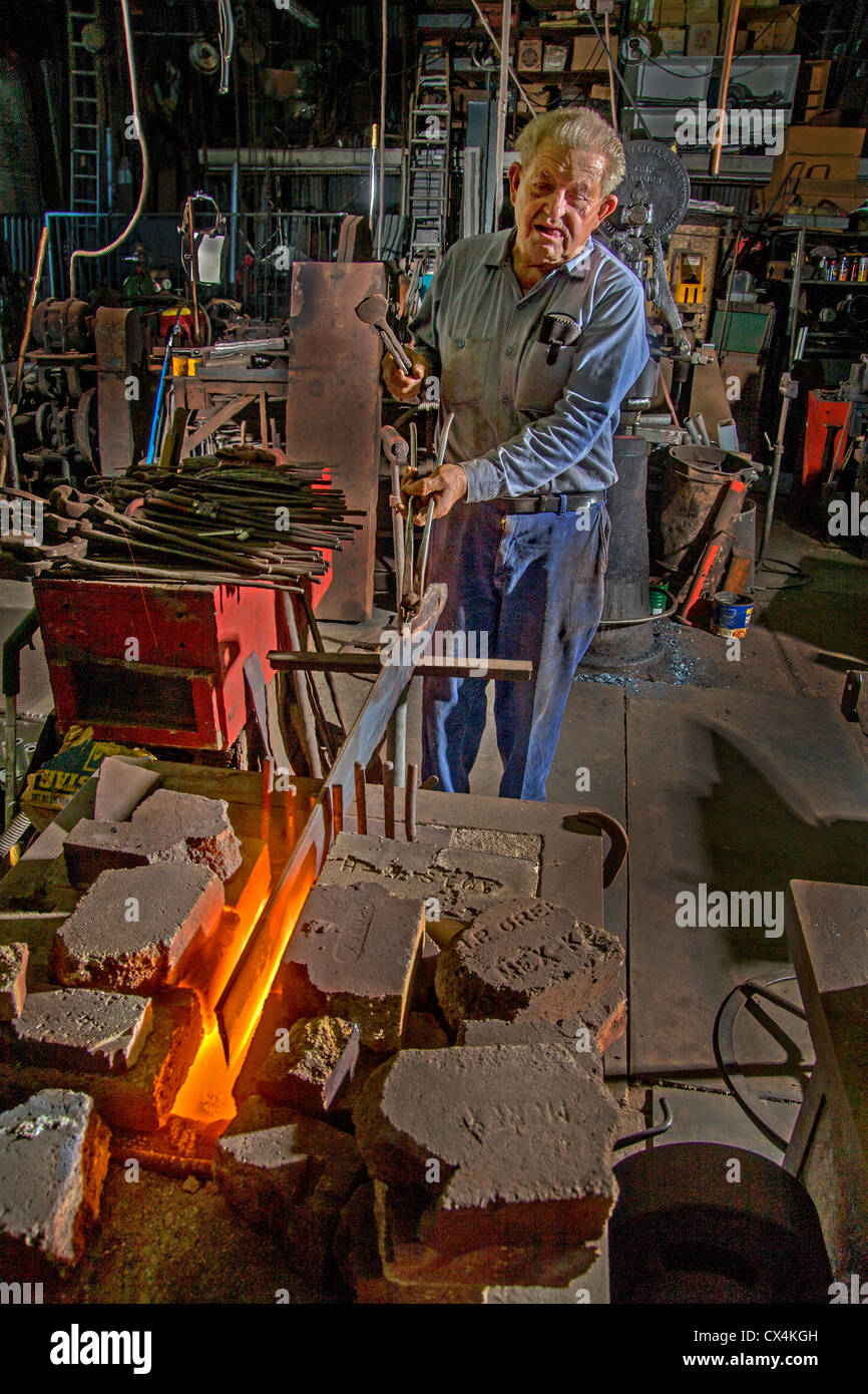 An elderly blacksmith in a Tustin, CA, barn built in 1912 heats a hot ...