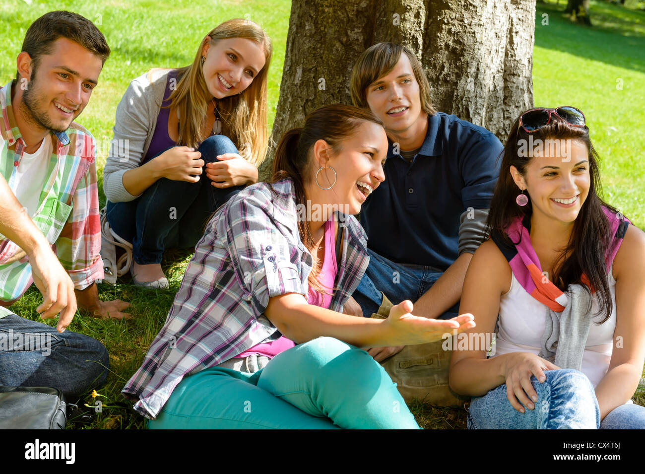 Students relaxing in schoolyard teens meadow park laughing campus young ...