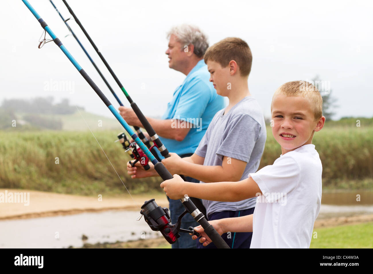 two young grandsons fishing with their grandpa by the lake Stock Photo ...