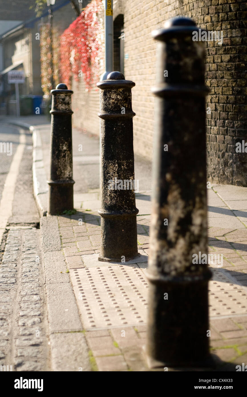 Three old iron bollards on pavement in sunlit street Stock Photo - Alamy