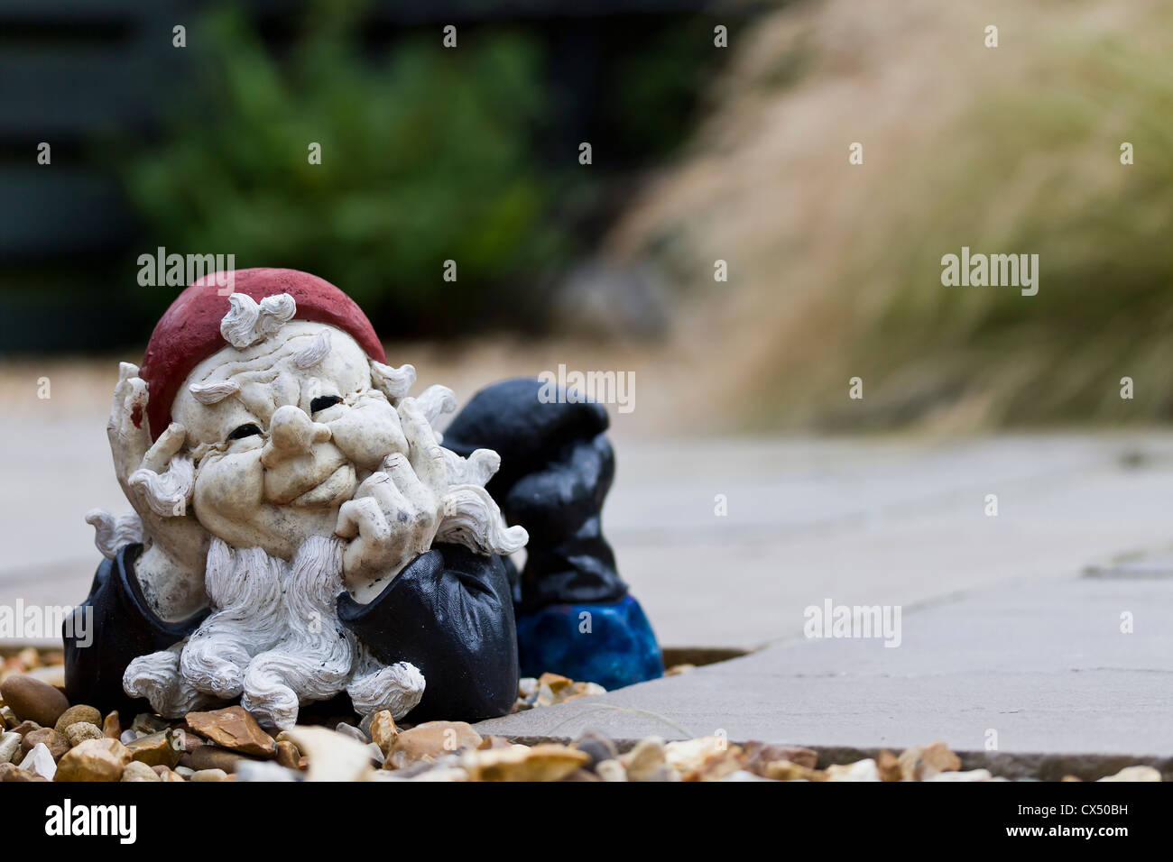 Garden gnome lying down with his feet up thinking Stock Photo - Alamy