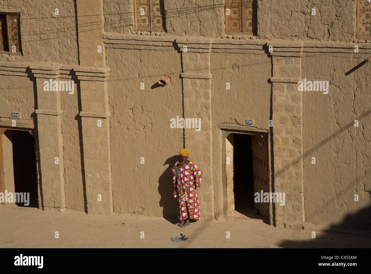 A woman standing outside a typical house in a street in Timbuktu, Mali ...