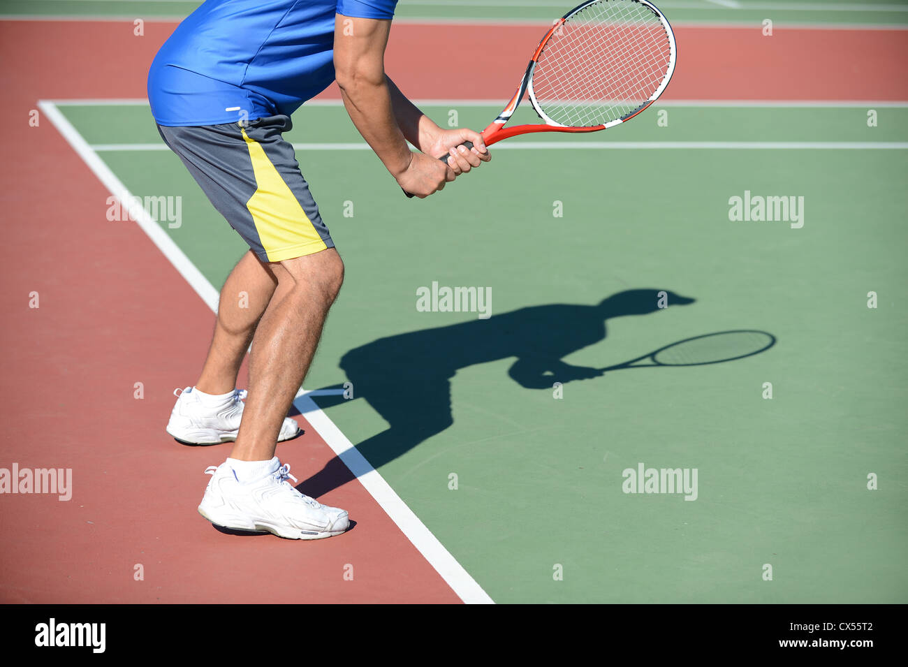 Tennis Player holding racket casting shadow on court Stock Photo - Alamy