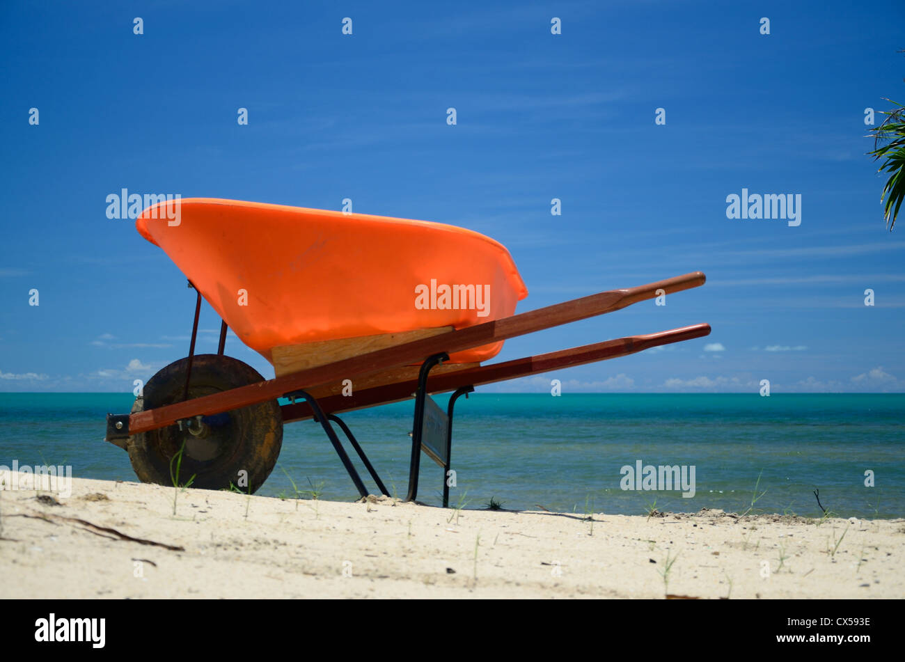 Orange wheelbarrow with wooden handles on a beach Stock Photo - Alamy