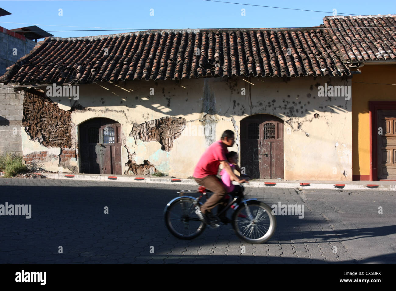 Man and child on bicycle ride past run down houses in the city of ...