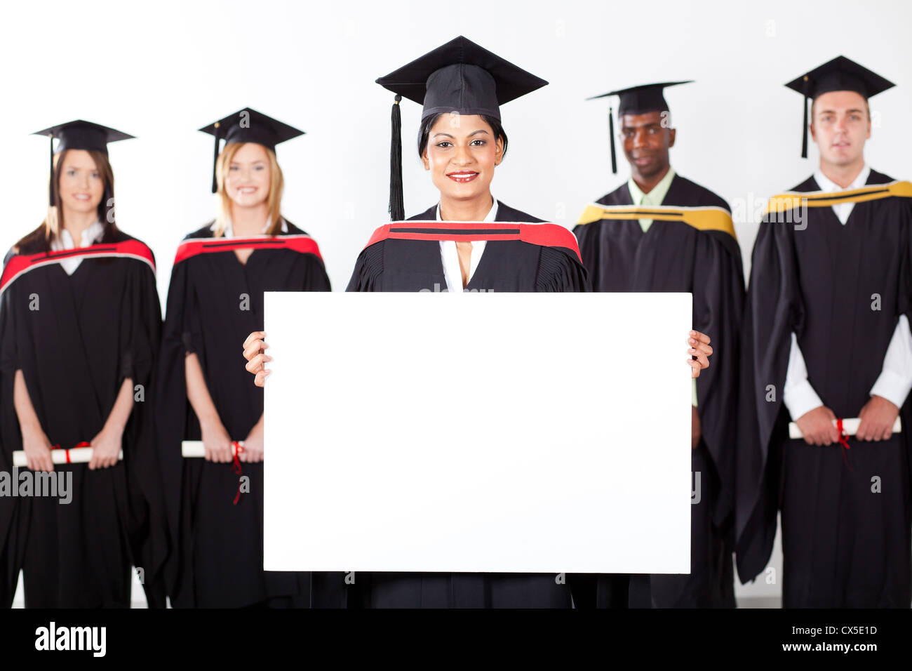 female Indian graduate holding white board with classmates in ...