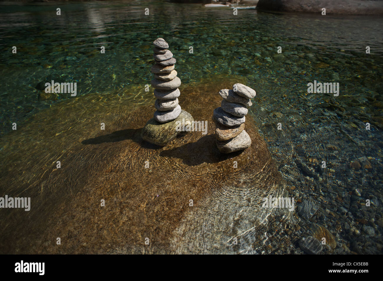 Stacked stones on a rock in the river of Verzasca. Green water flowing ...