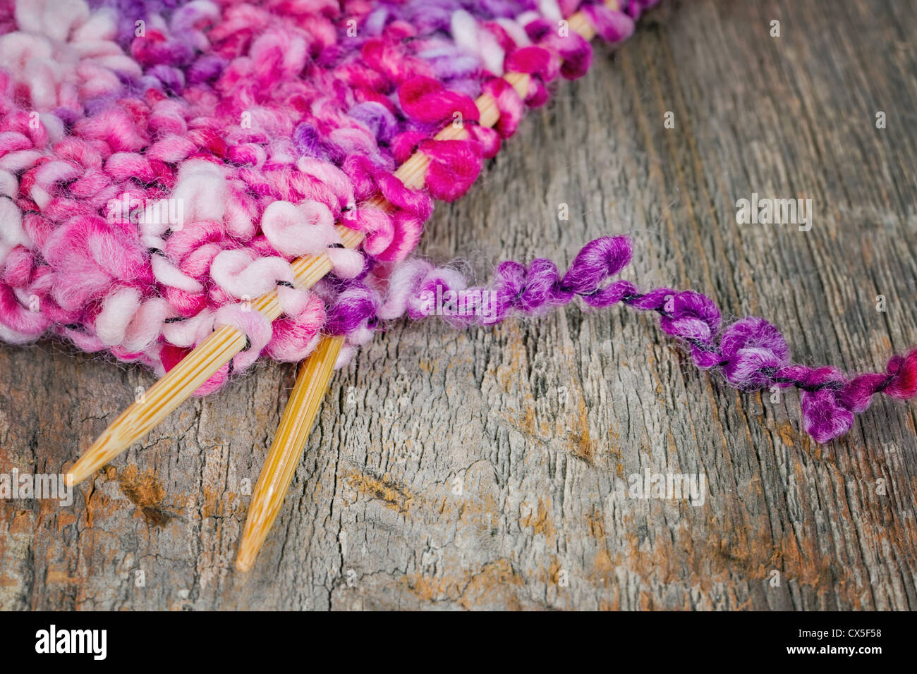 Colorful pink and purple knitting and wooden needles on rustic ...