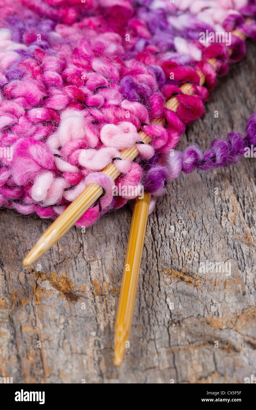 Colorful pink and purple knitting and wooden needles on rustic ...