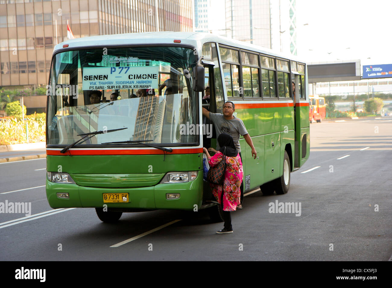 A bus stopping in the middle of the street to pick up a passenger Stock ...