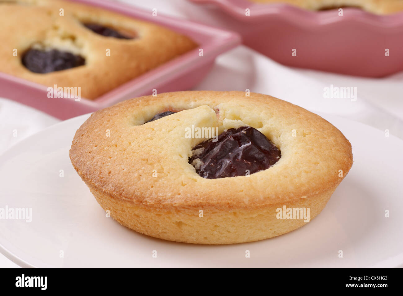 Small plum cake on a white cake stand. Plum cakes in pink pottery cake ...