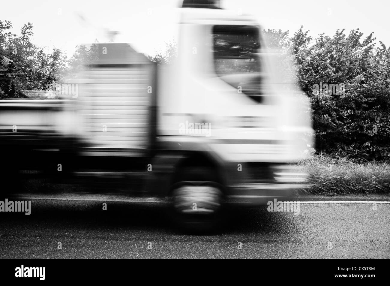 A lorry driving down a road with movement Stock Photo - Alamy