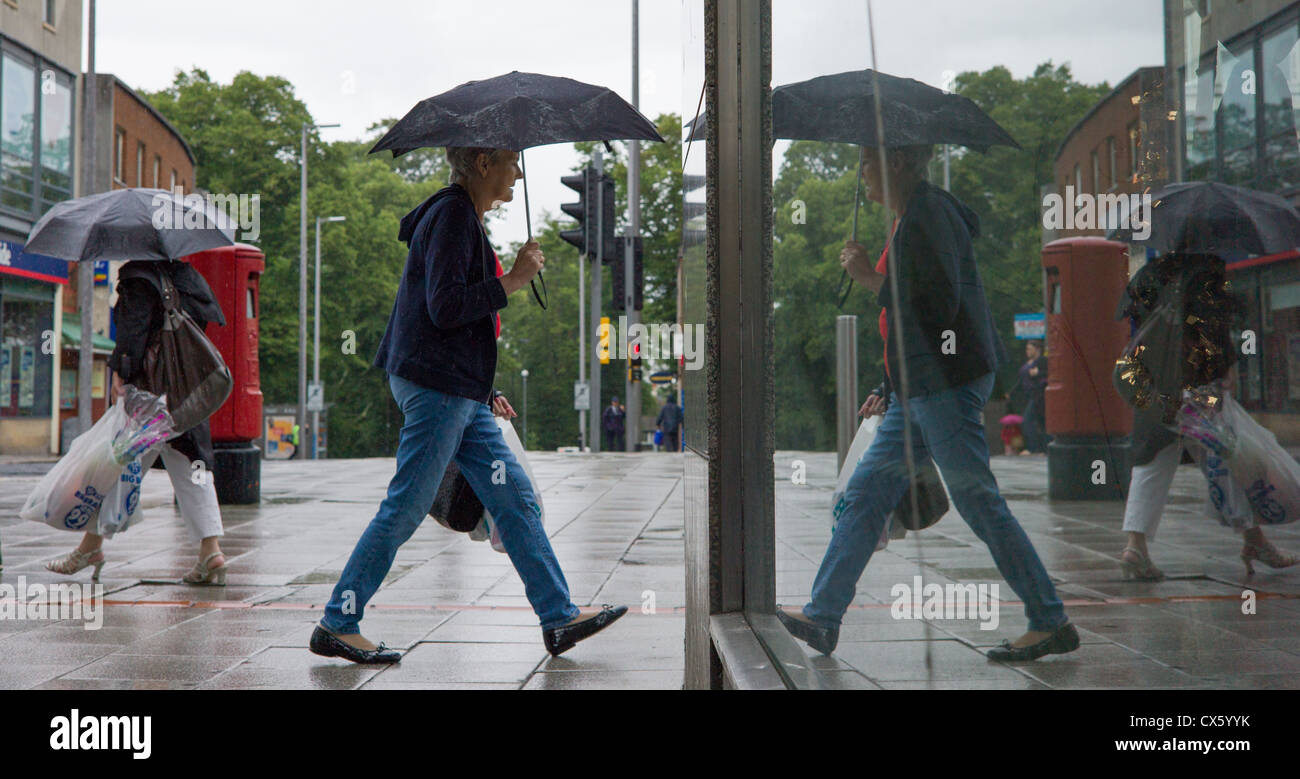 a reflection in a window of people walking in the rain with umbrellas ...