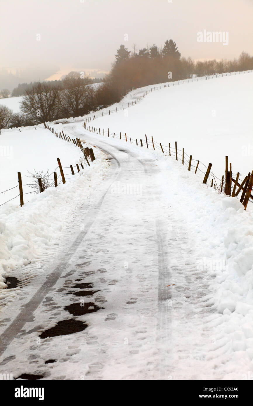 An asphalt country road in a snow storm, fields at small town Prüm ...