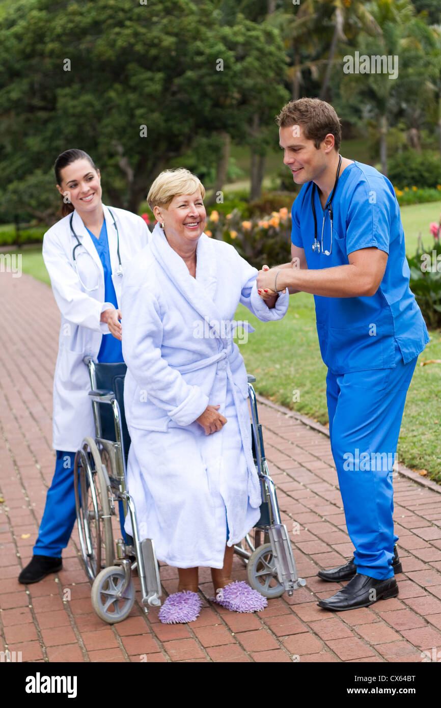 young caring doctor and nurse helping senior patient get up from ...