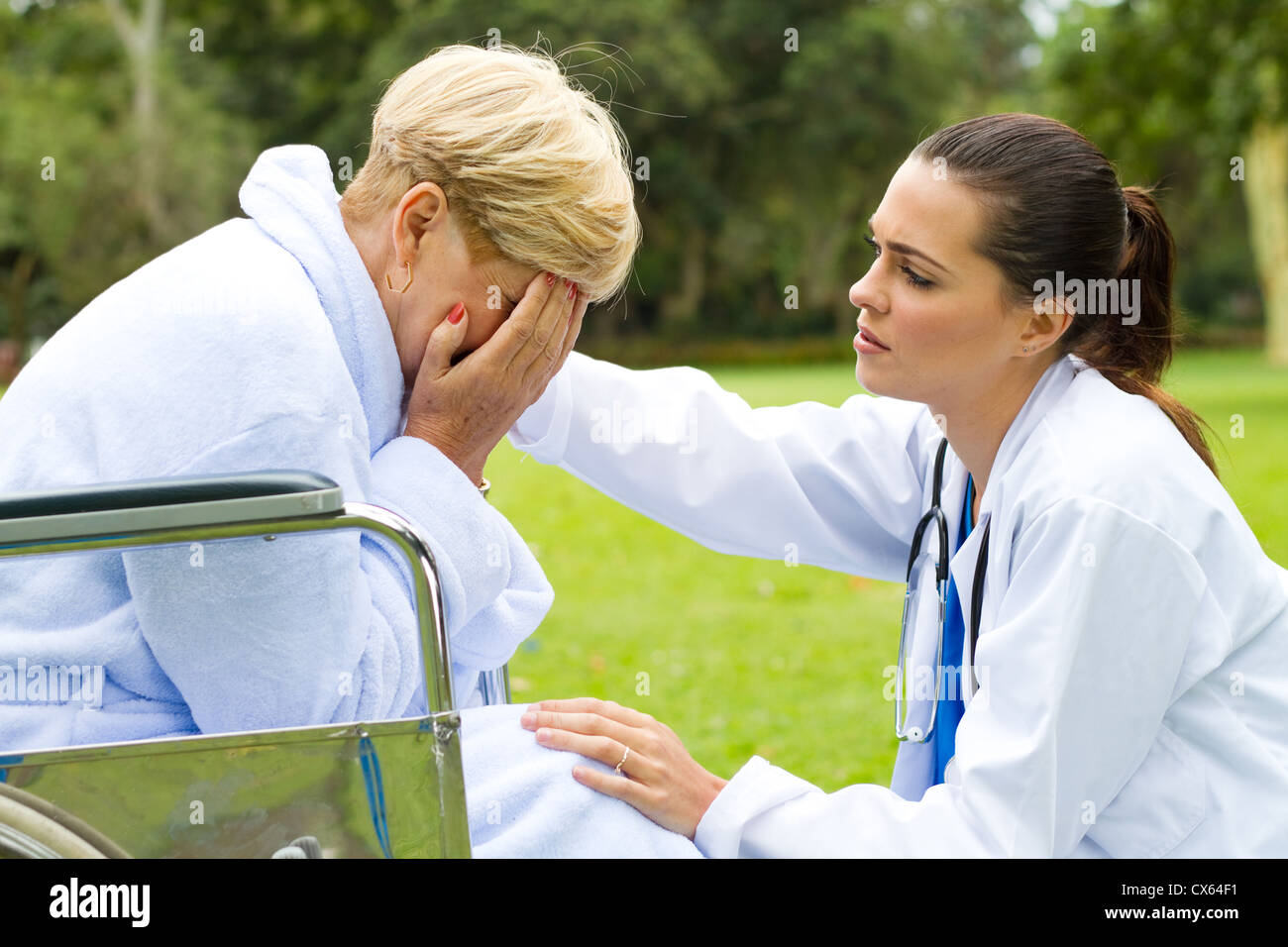 caring young female doctor comforting a lonely disabled senior patient ...